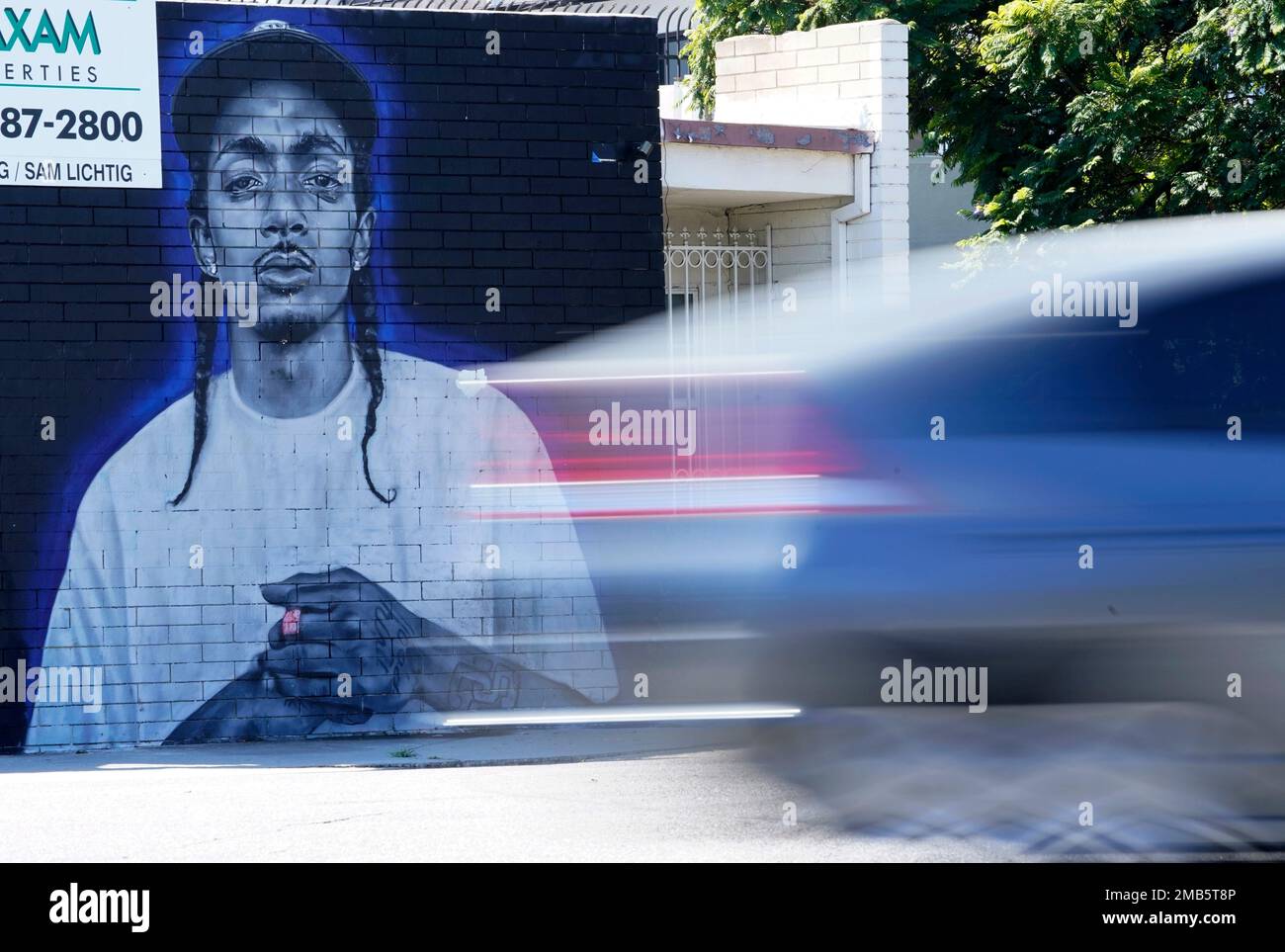 A car blurs past a street mural of the late rapper Nipsey Hussle ...