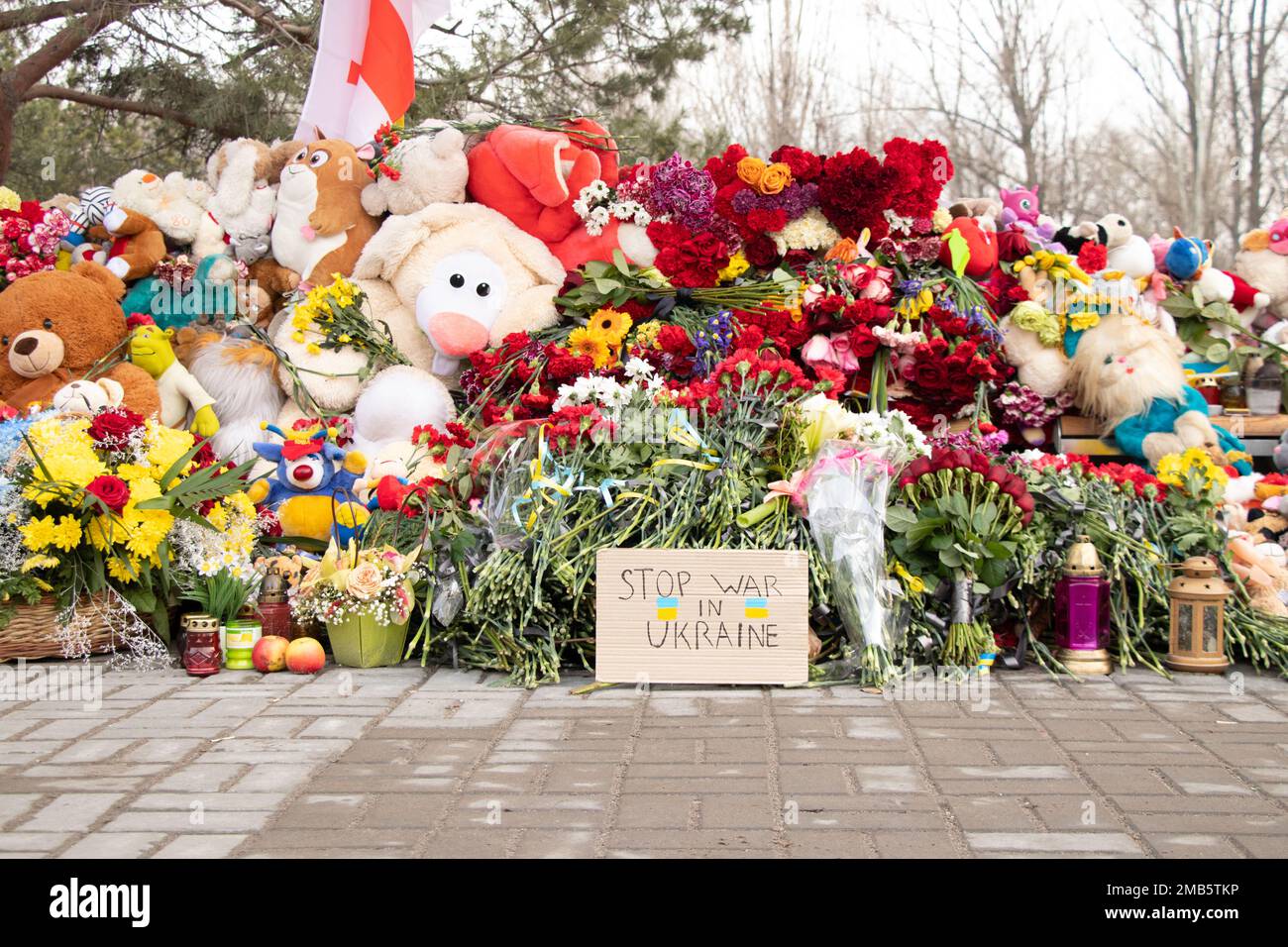 Toys and flowers lie at a trolleybus stop next to a house blown up by a ...