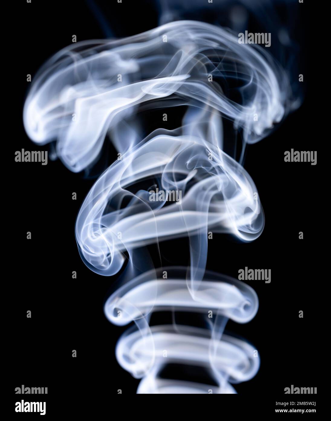 Pattern formed by smoke swirling round in front of a plain, black ...