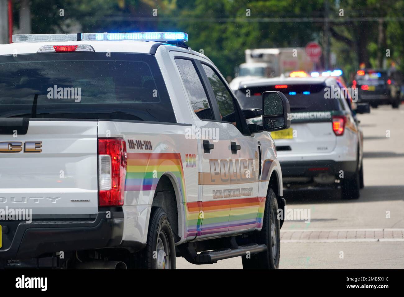 A line of police cars painted in the colors of the rainbow pride flag ...