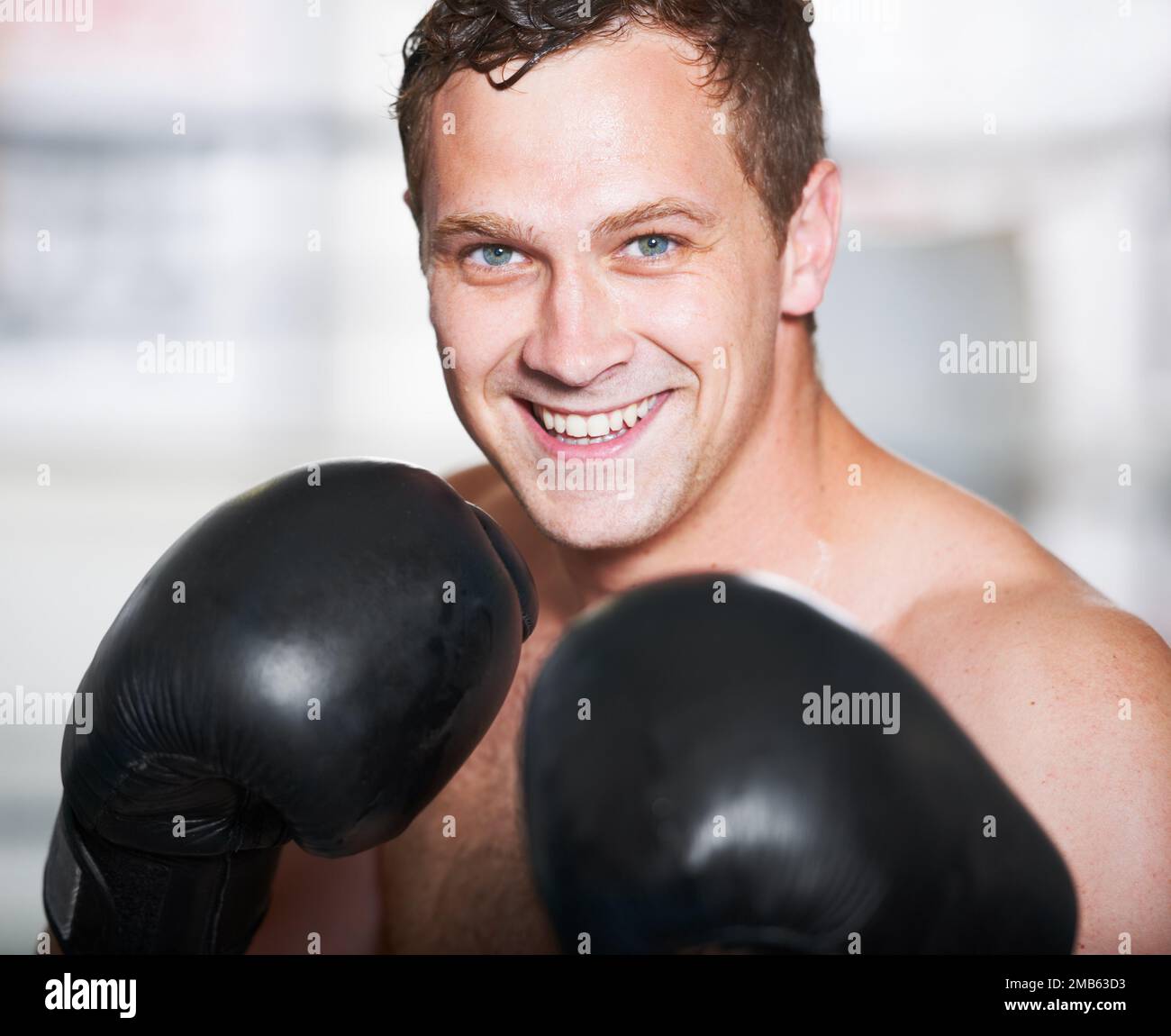 Fit and ready. A young handsome boxer smiling at you with his gloves up ...