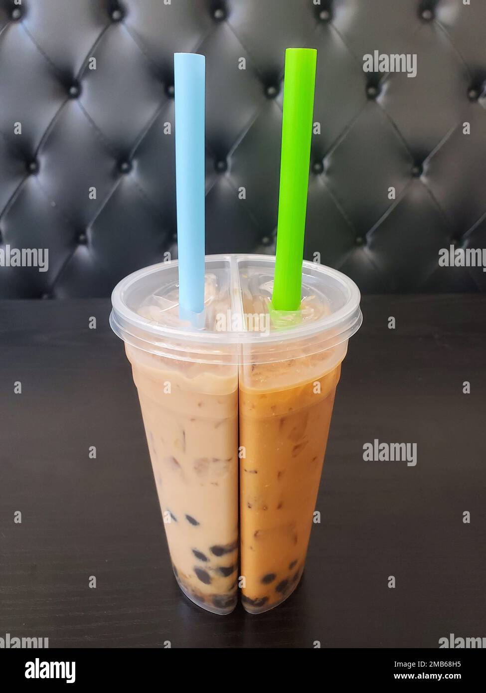 A vertical shot of two different bubble teas in a plastic cup with ...