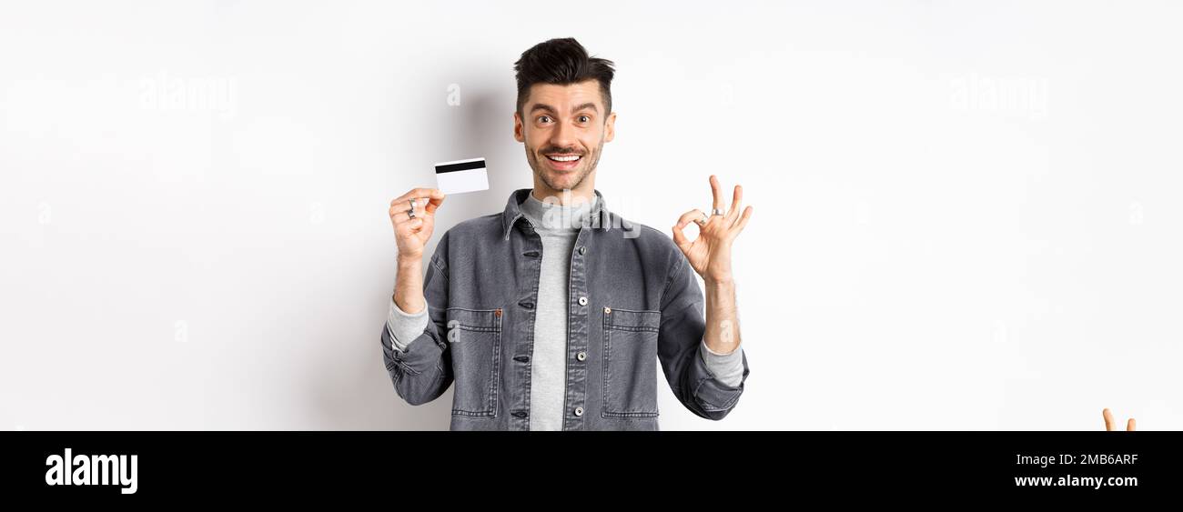 Very good. Smiling guy with plastic credit card showing okay sign ...
