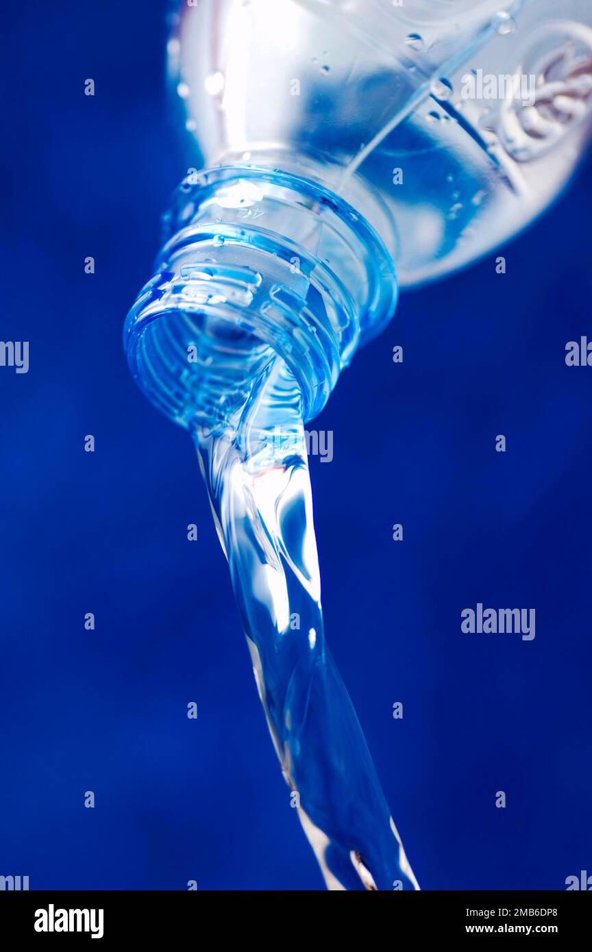stream of water pouring out from bottle over blue background Stock ...