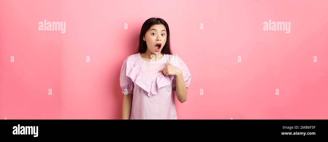 Surprised asian girl gasping wondered, pointing at herself, being ...