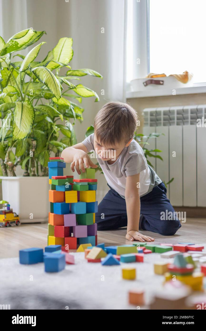 Confident male kid building fortress tower architecture wooden bricks ...