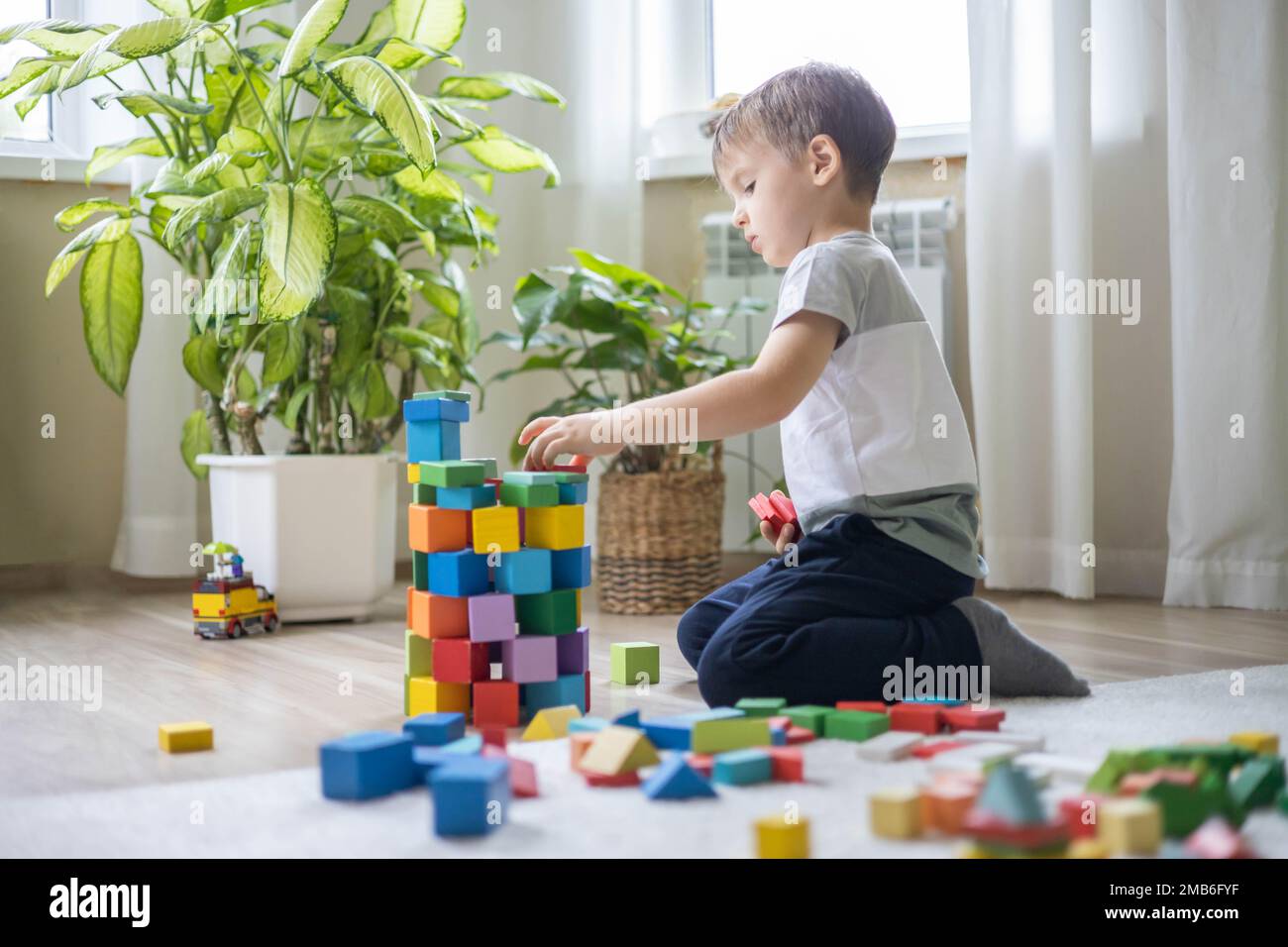 Confident male kid building fortress tower architecture wooden bricks ...