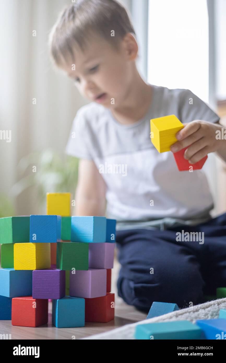 Confident male kid building fortress tower architecture wooden bricks ...