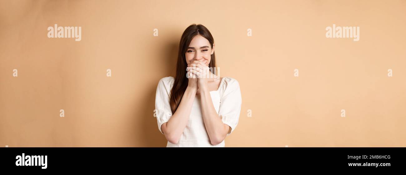 Happy girl laughing and covering mouth with hands, hiding her smile and ...
