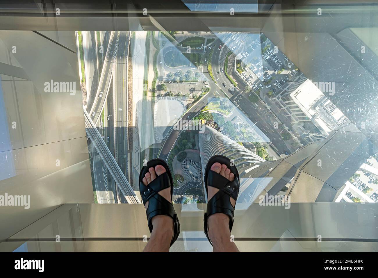 Tourists posing on a glass floor in a skyscraper. feet on the glass ...