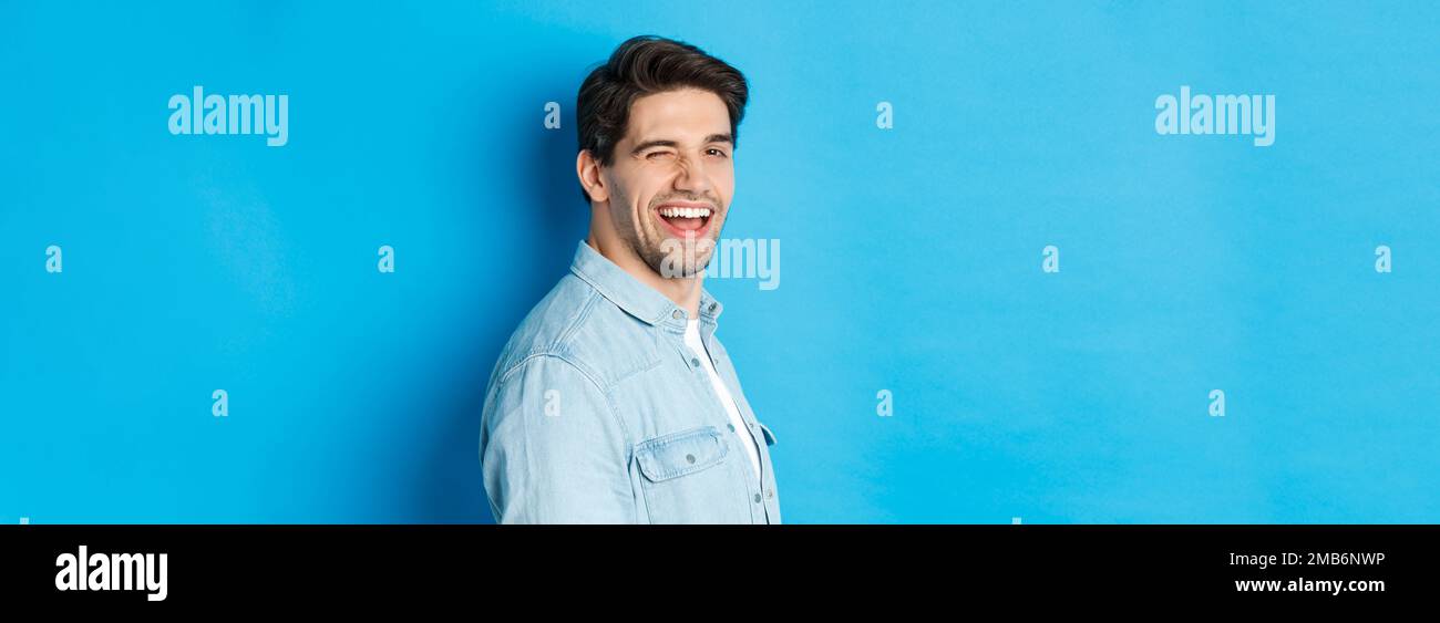 Happy and confident man turn head at camera, winking and smiling ...