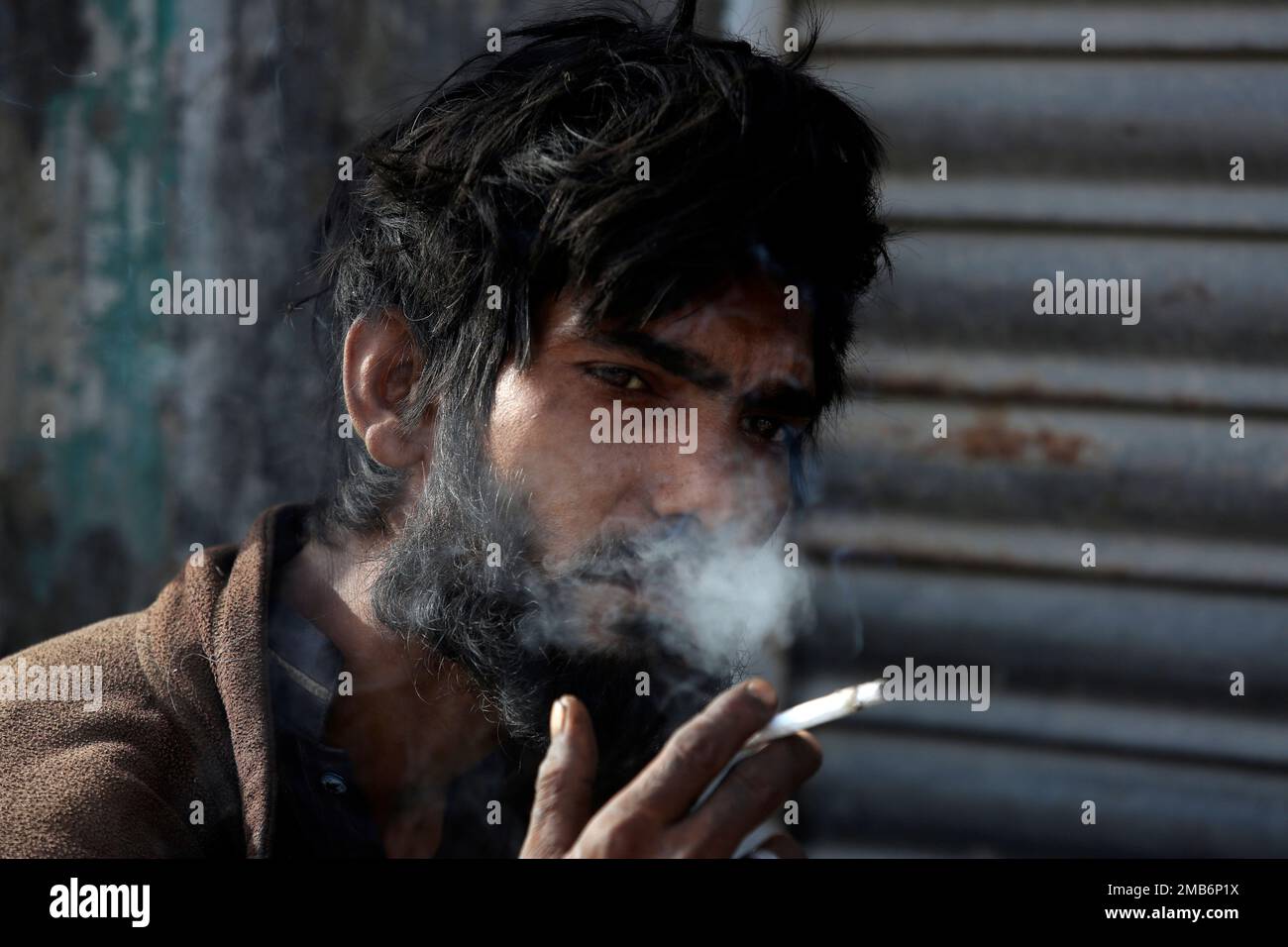 A Pakistani drug addict smokes heroin on a roadside in Karachi ...