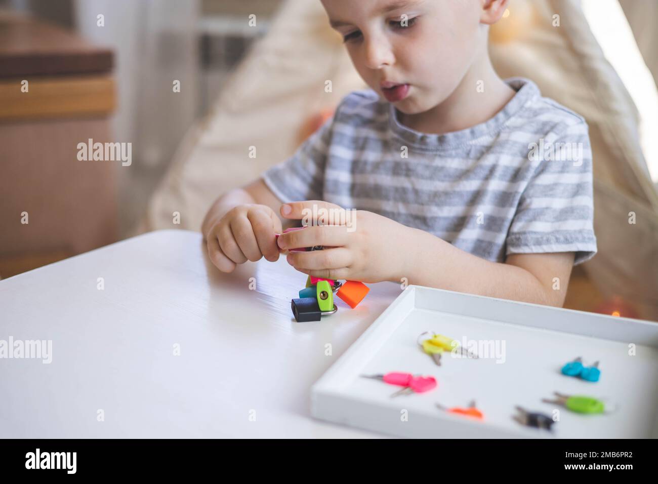 The child works with Montessori material with colored locks. Picks up ...