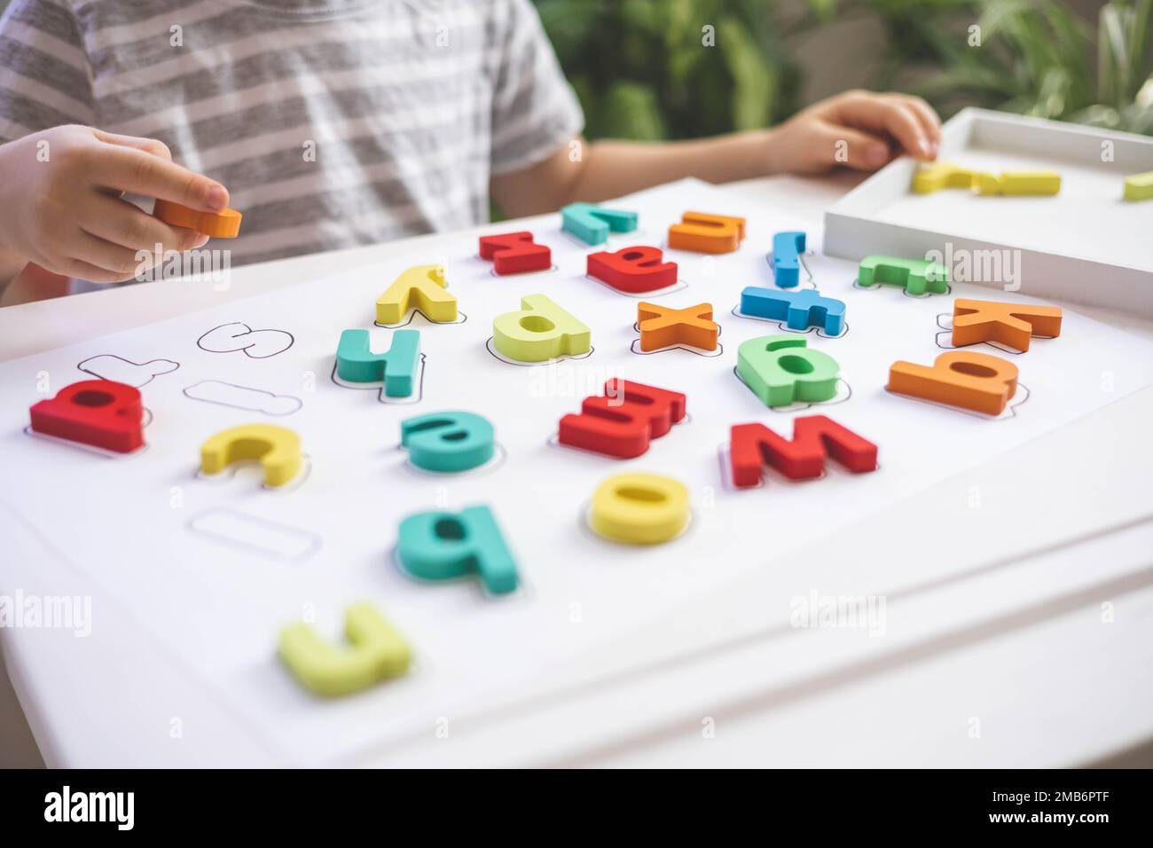 Male kid playing with wooden eco friendly alphabet letters board on ...