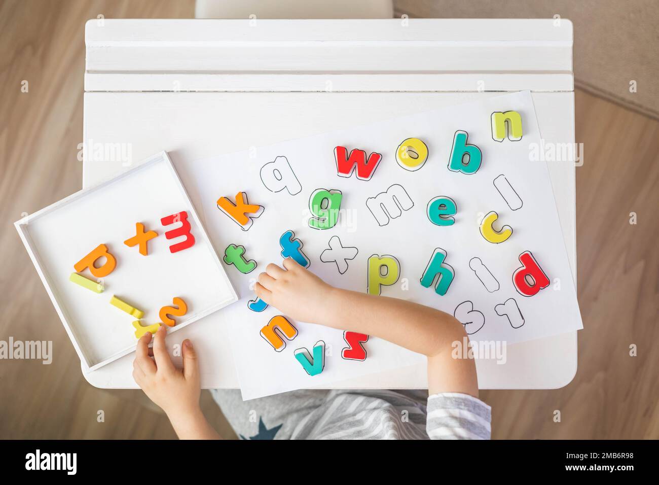 Childish hands holding alphabet wooden board with colored font letters ...