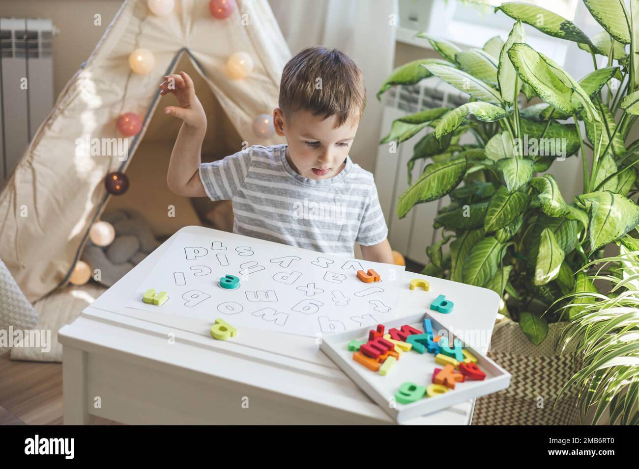 Male kid playing with wooden eco friendly alphabet letters board on ...