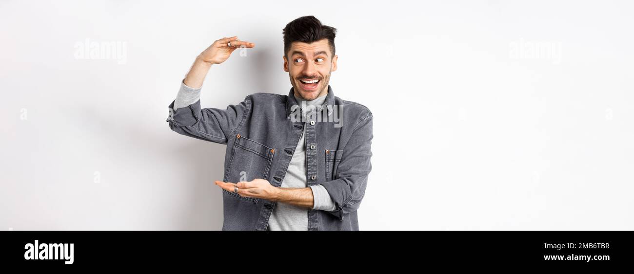 Excited guy looking at logo and showing big size thing, shaping large ...