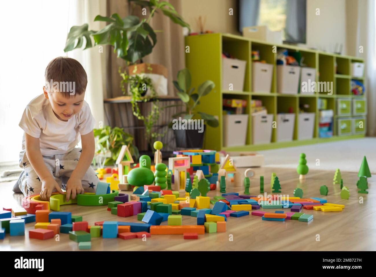 Funny baby boy playing multicolored arch Montessori wooden material ...