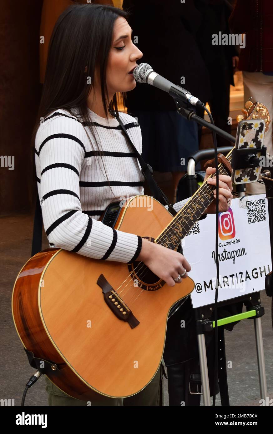 Female musician playing acoustic guitar and singing outdoor in the ...