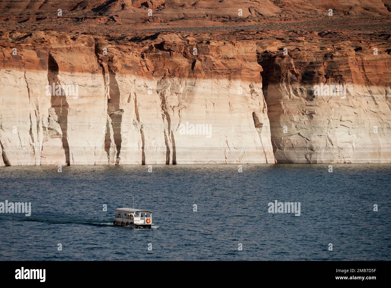 A boat floats past bathtub rings showing how low Lake Powell levels ...