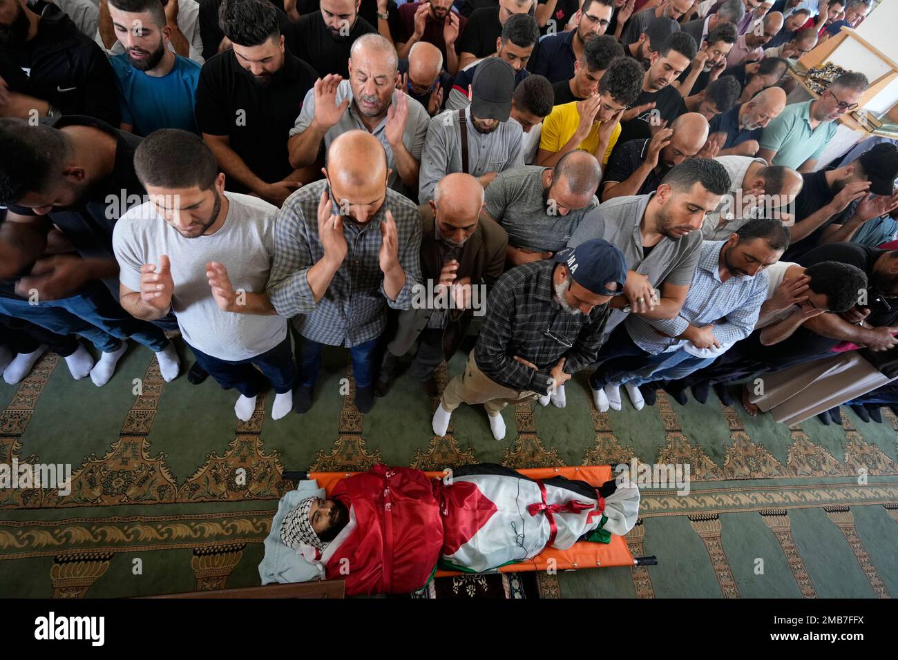 Palestinian mourners pray next to the body of Ali Harb, 27, who was ...