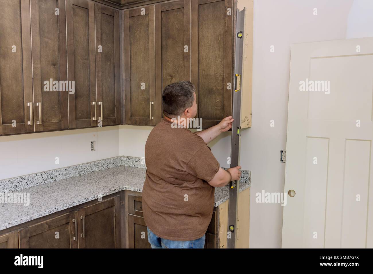 Worker holding level for leveling of new kitchen cabinets before it was ...