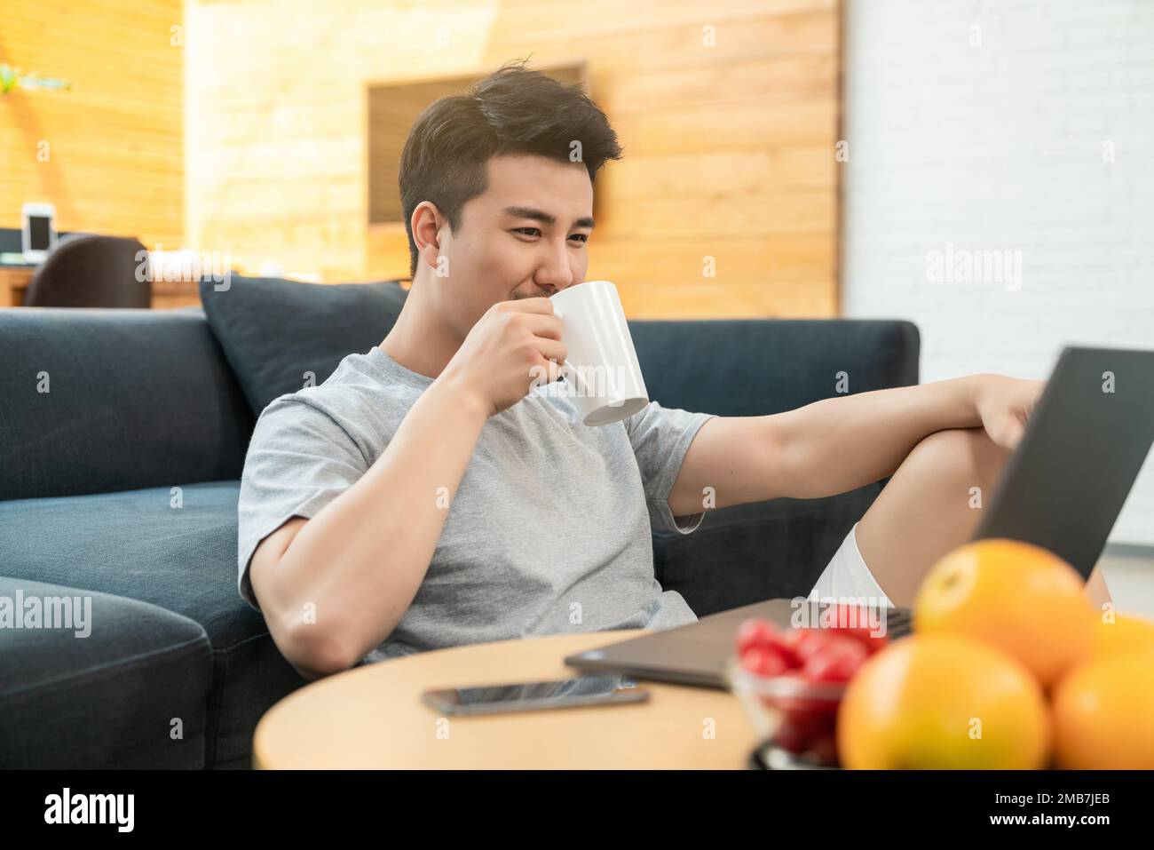 The young man sitting on the sofa side use the computer Stock Photo - Alamy