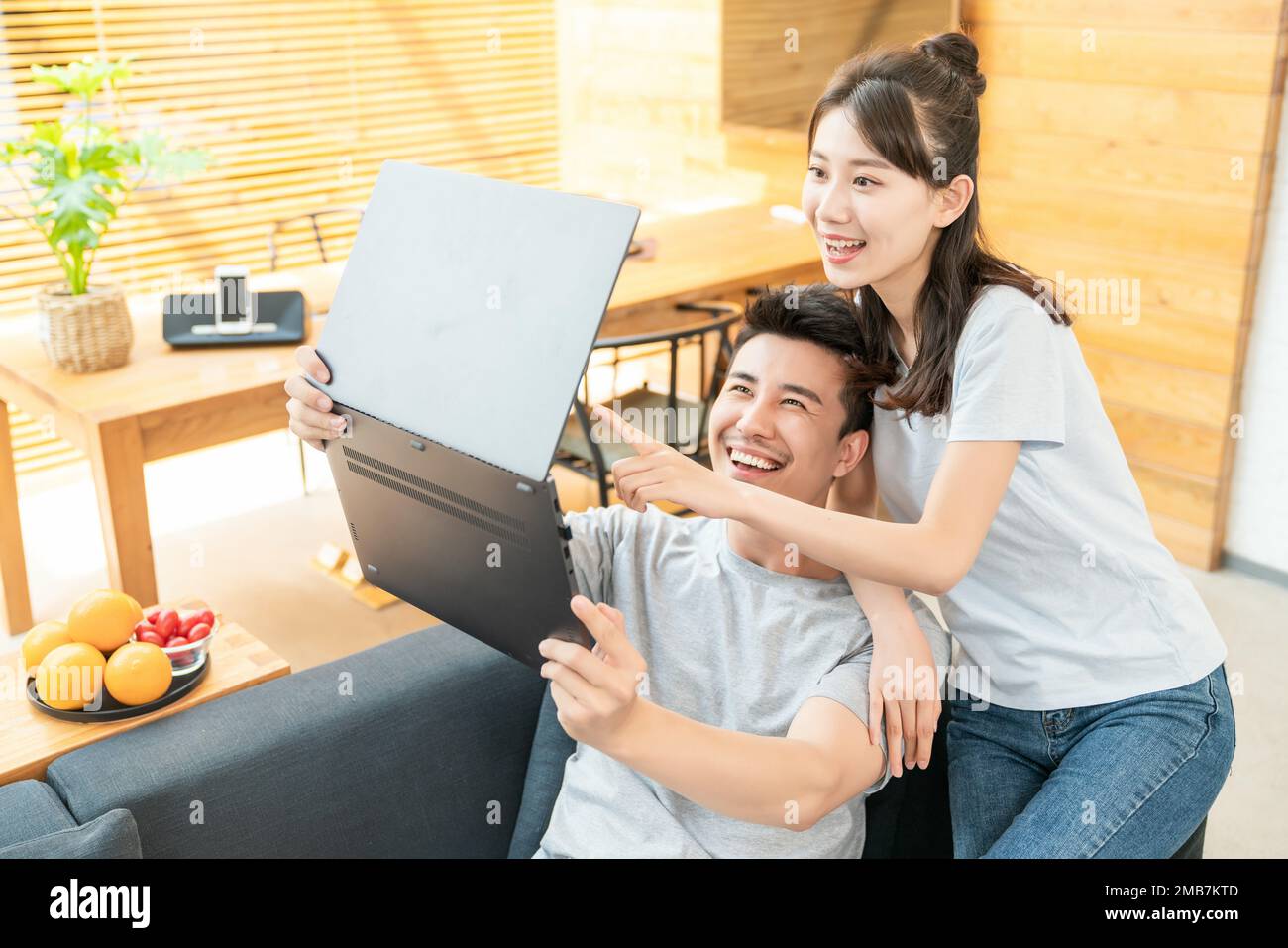 Young couples to use a computer on the sofa Stock Photo - Alamy