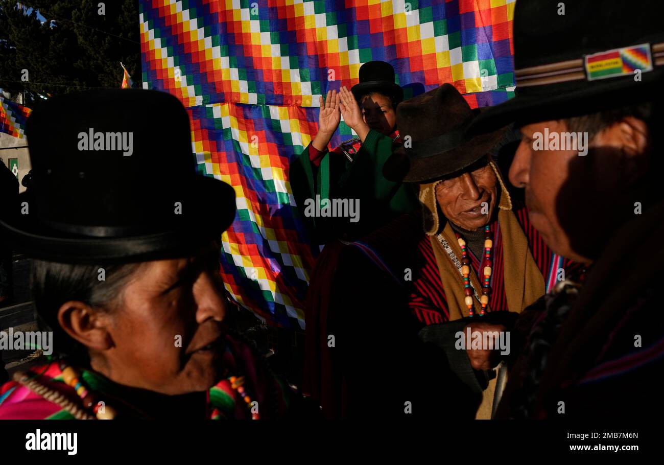 Aymaras attend a New Year's ritual, backdropped by a Wiphala, a ...