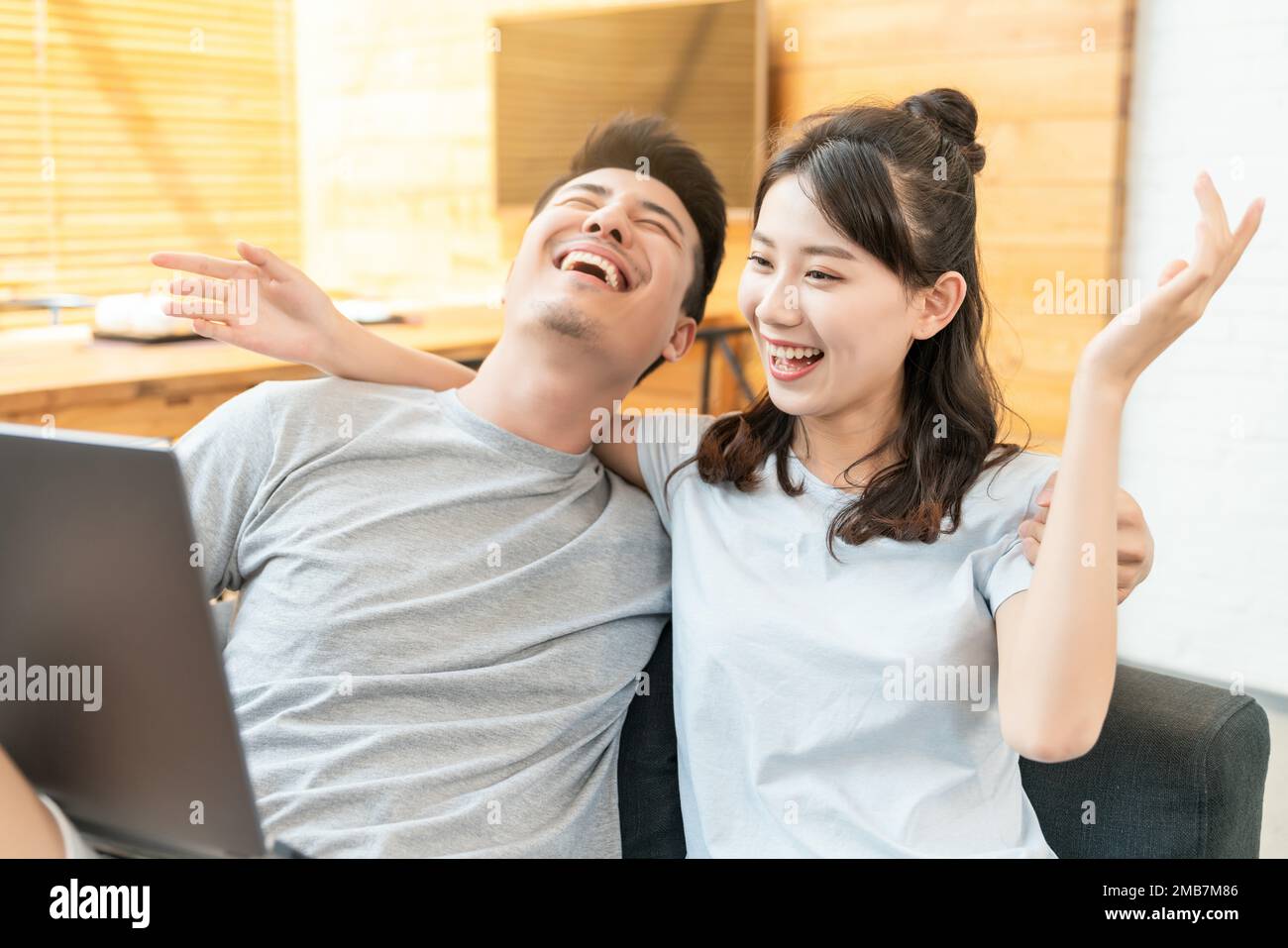Young couples to use a computer on the sofa Stock Photo - Alamy