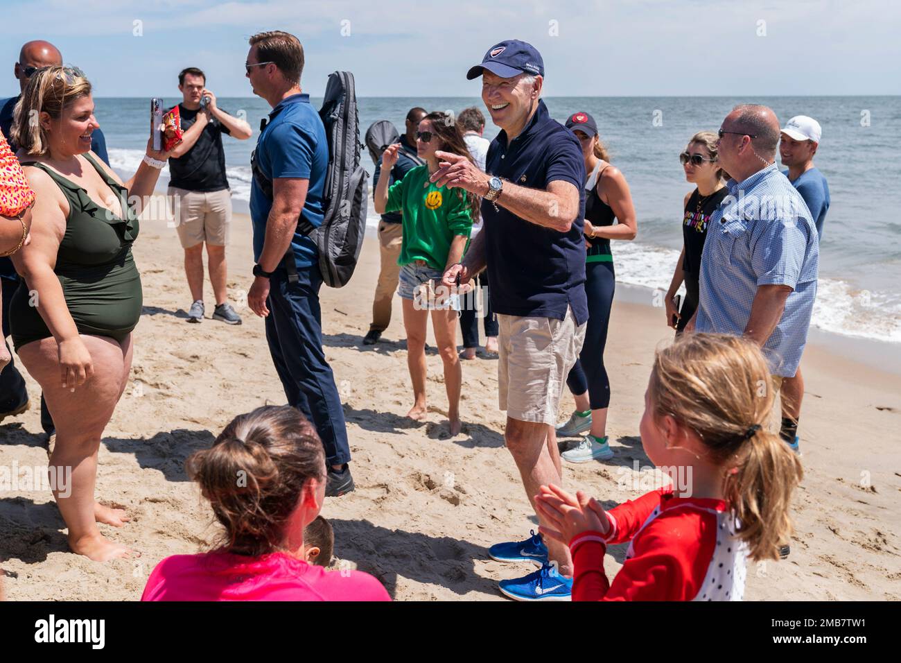 President Joe Biden talks to people as he walks on the beach with his ...
