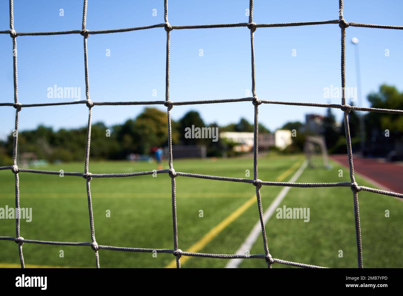 String net at a sports playground with green grass and blue sky in the ...