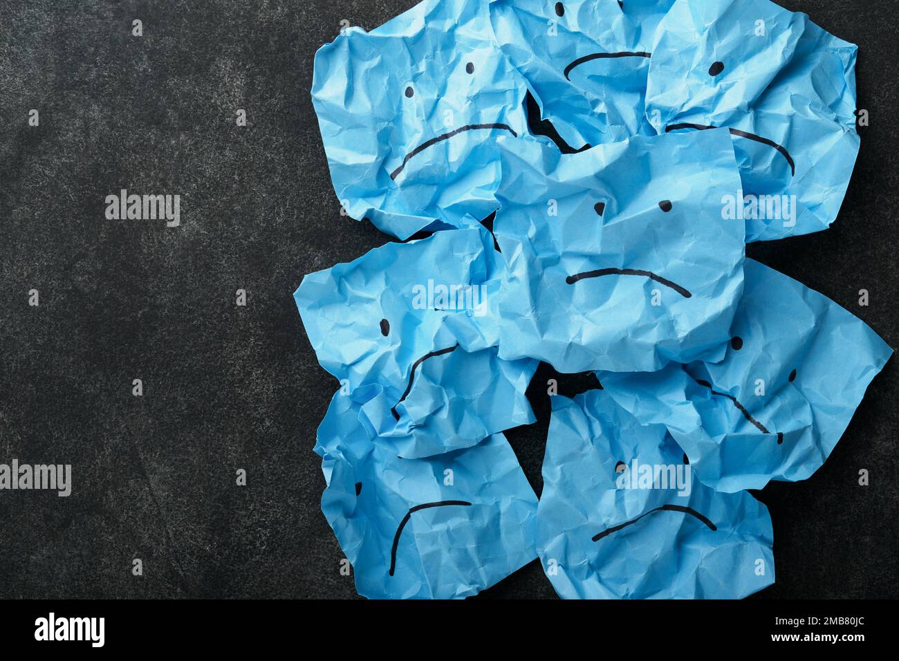 Blue crumpled sticky notes blank with drawing sad face on black ...