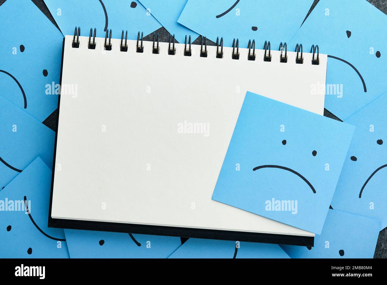 Blue sticky notes blank with drawing sad face on black background with ...