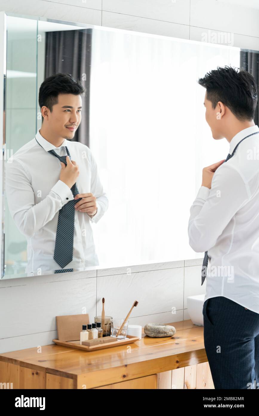 A young man in front of the mirror tie Stock Photo - Alamy