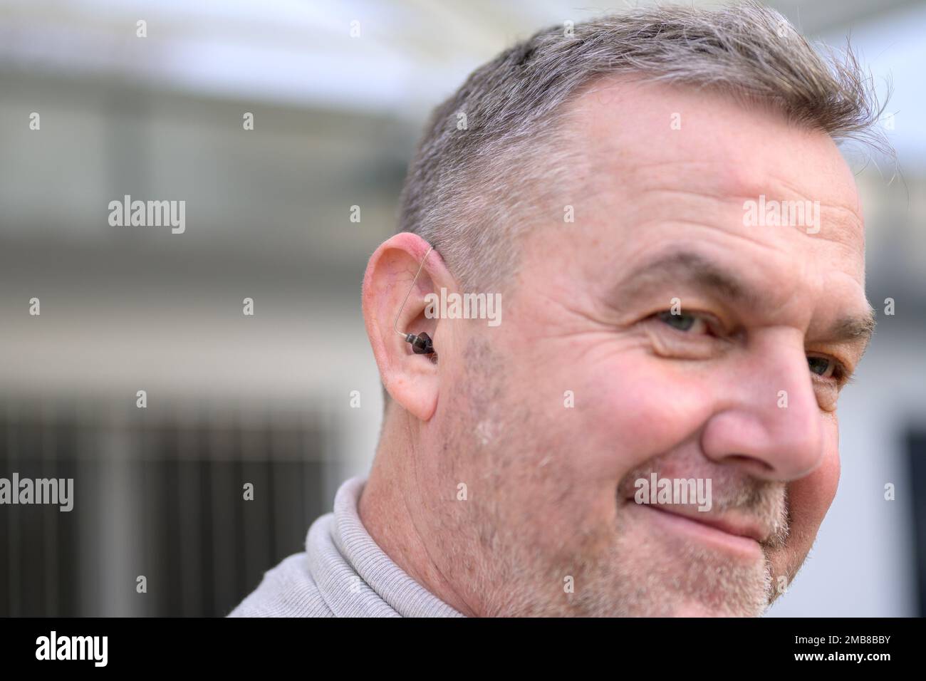 Side view of a middle aged gray haired hard of hearing man in his ...