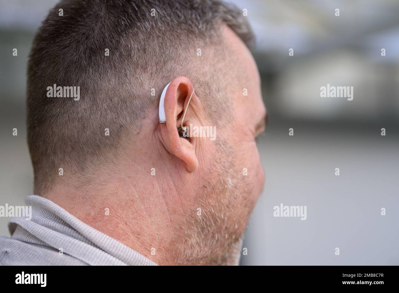 Rear view of a middle aged gray haired hard of hearing man in his ...