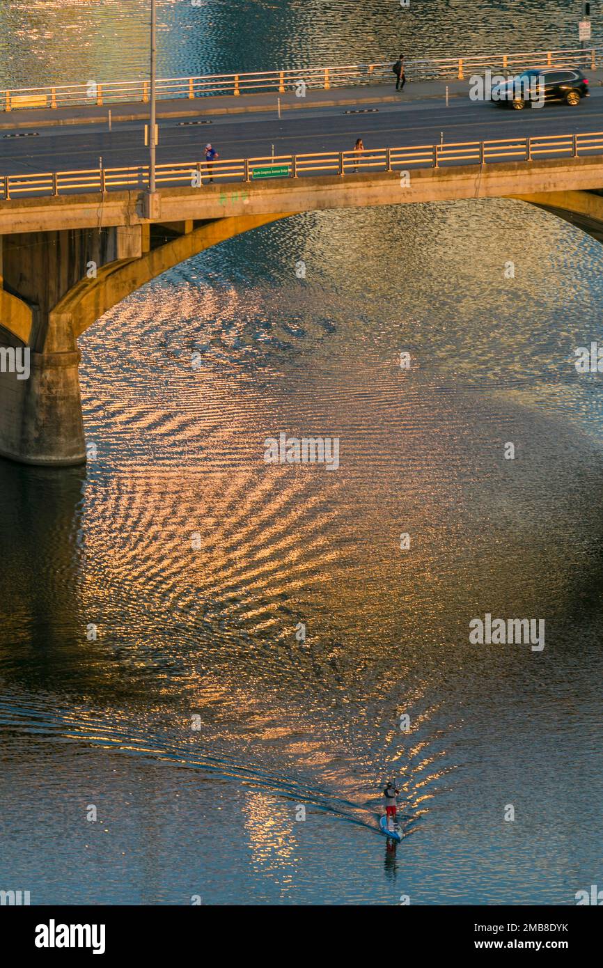 Standup paddleboarder passes Congress Bridge on Ladybird Lake in Austin ...