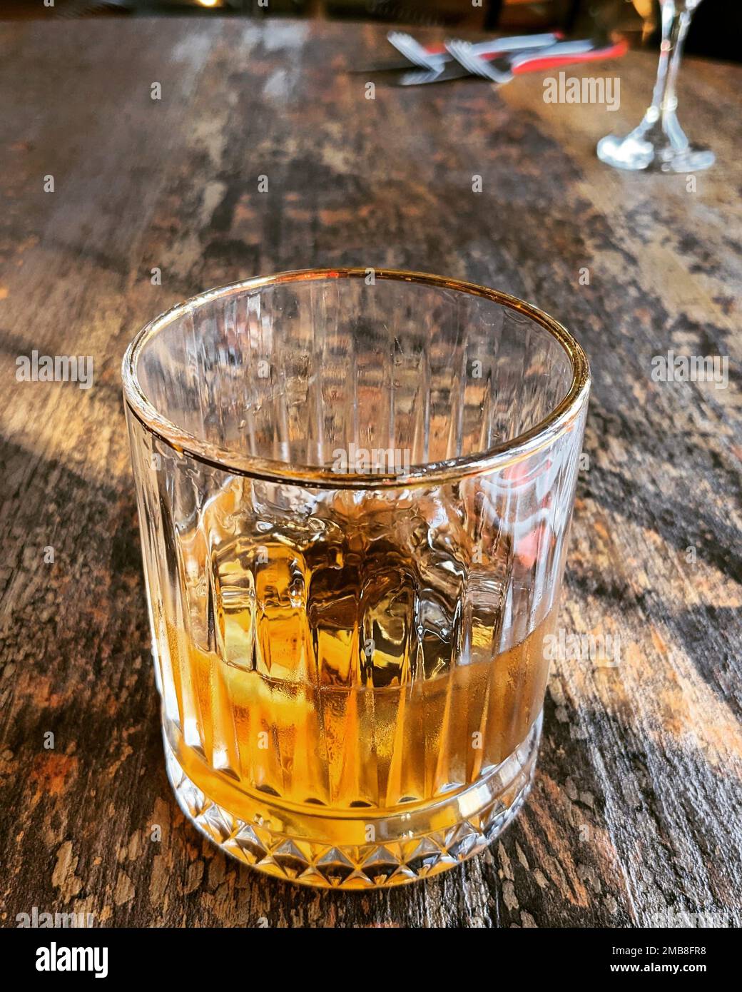 A vertical of the alcohol with ice in a glass put on the wooden table ...