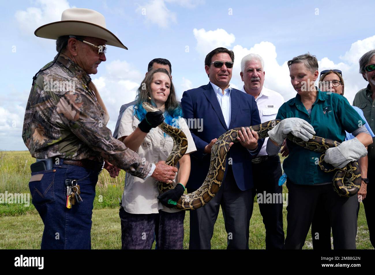 Florida Gov. Ron DeSantis, center, holds a Burmese python at a media ...