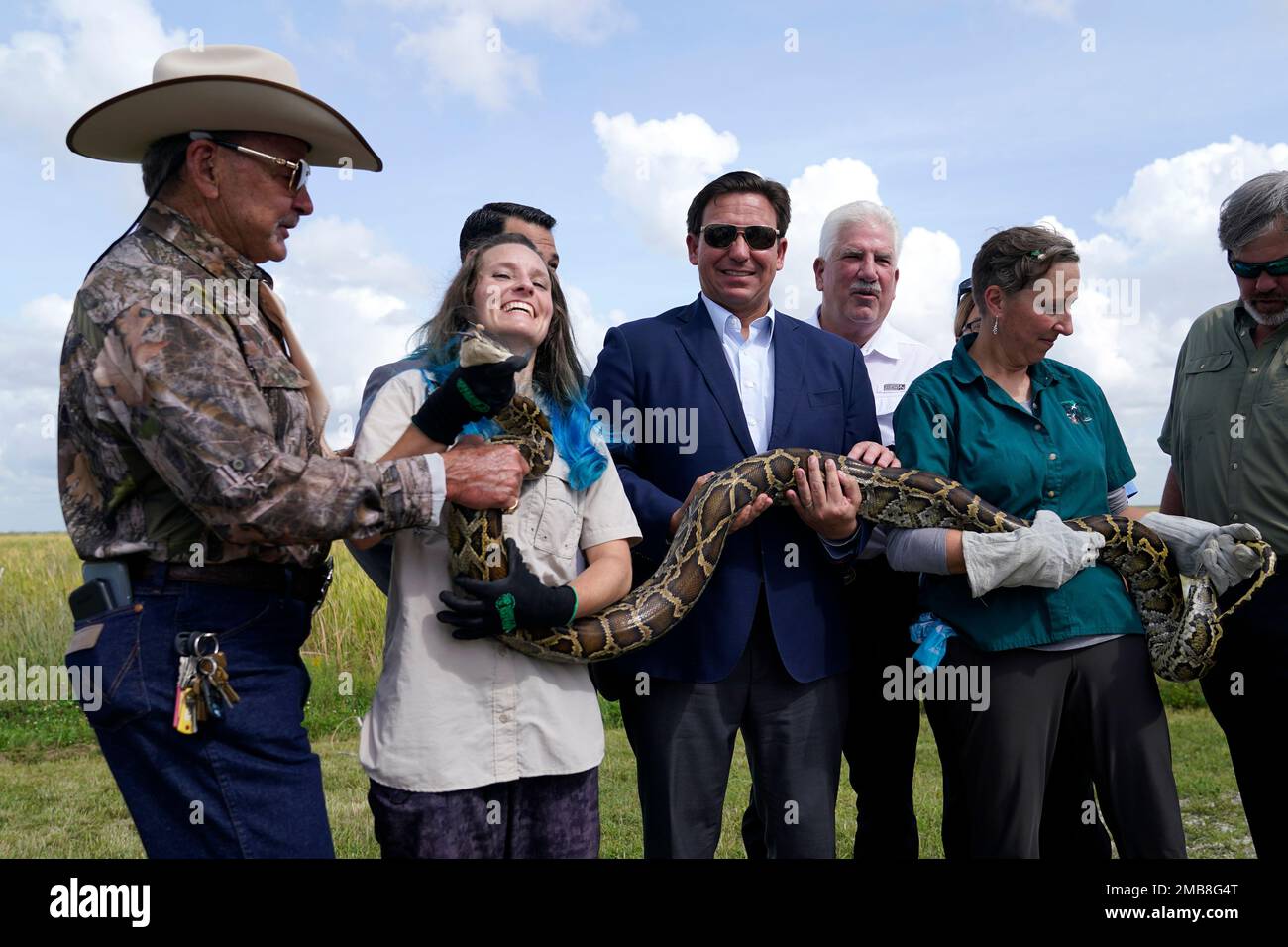 Florida Gov. Ron DeSantis, center, holds a Burmese python at a media ...