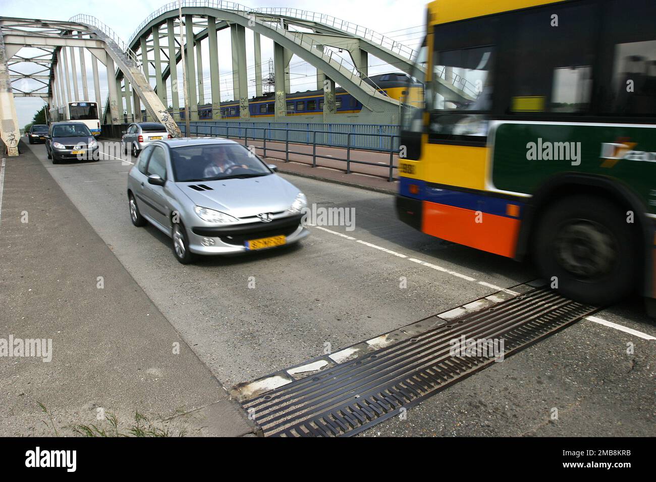 Netherlands, Utrecht. Cars, bus and train passing a bridge with a steel ...