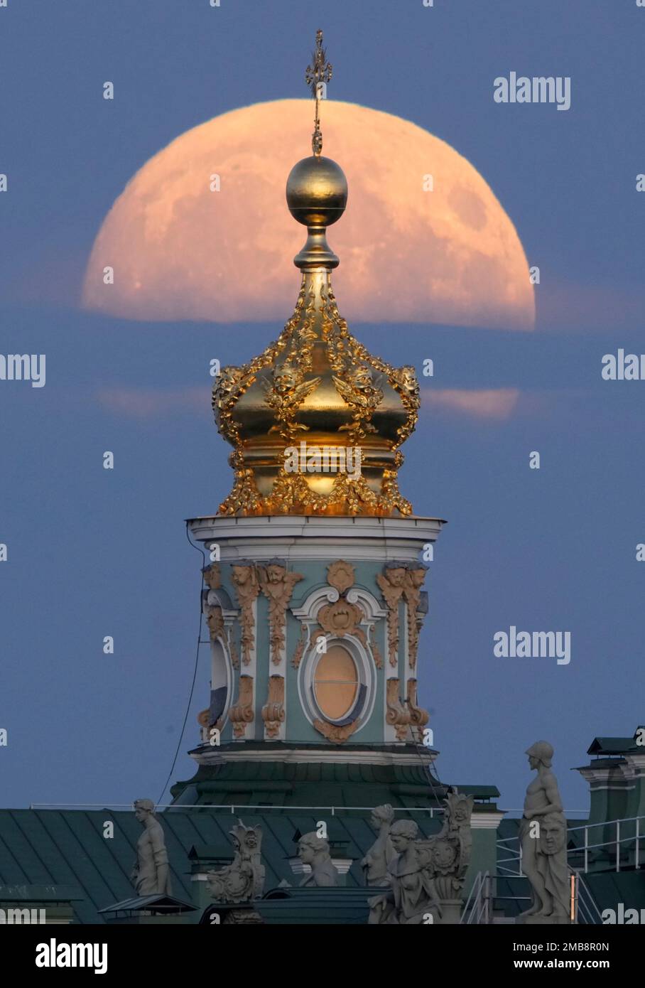 The full moon rises in the clouds over a church in St. Petersburg ...