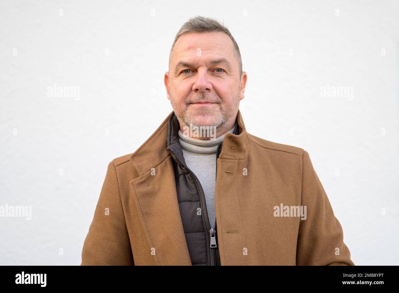 Portrait of a middle aged man with a gentle smile in a brown coat ...