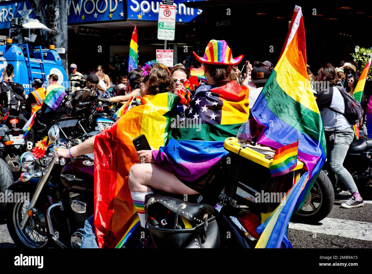 Participants draped in the pride flag while riding a Harley-Davidson ...