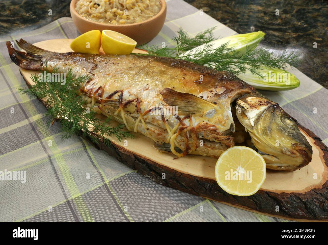 Stuffed roasted carp served with lemon slices, peas with cabbage and dill Stock Photo - Alamy