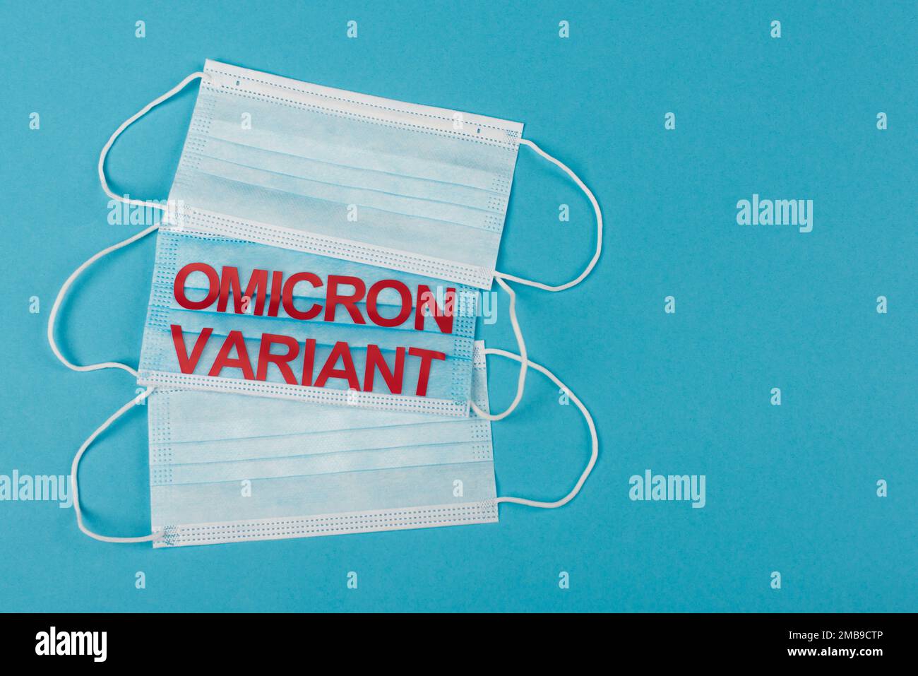 Top view of medical masks with omicron variant lettering on blue ...