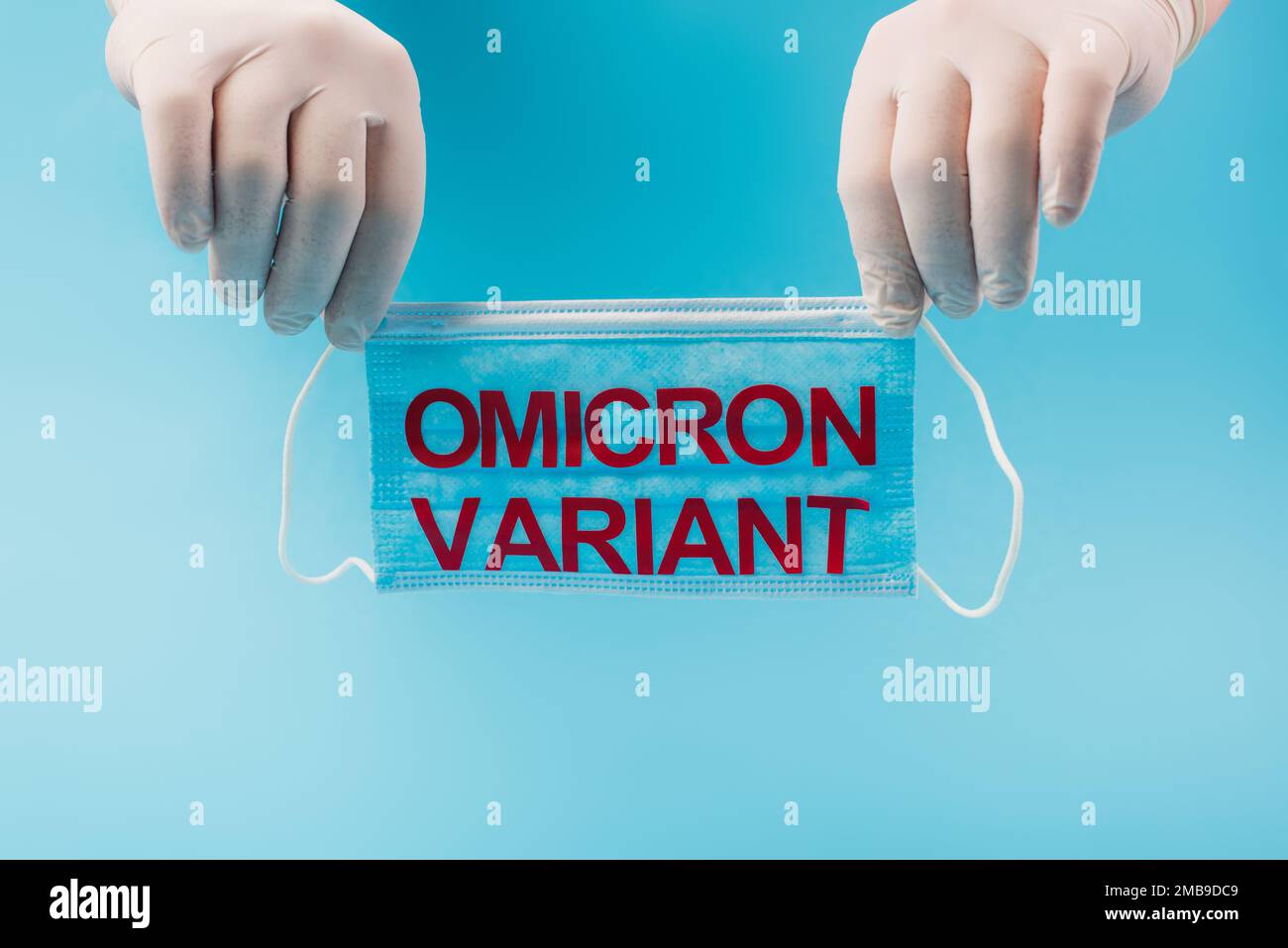 Cropped view of doctor in latex gloves holding medical mask with ...