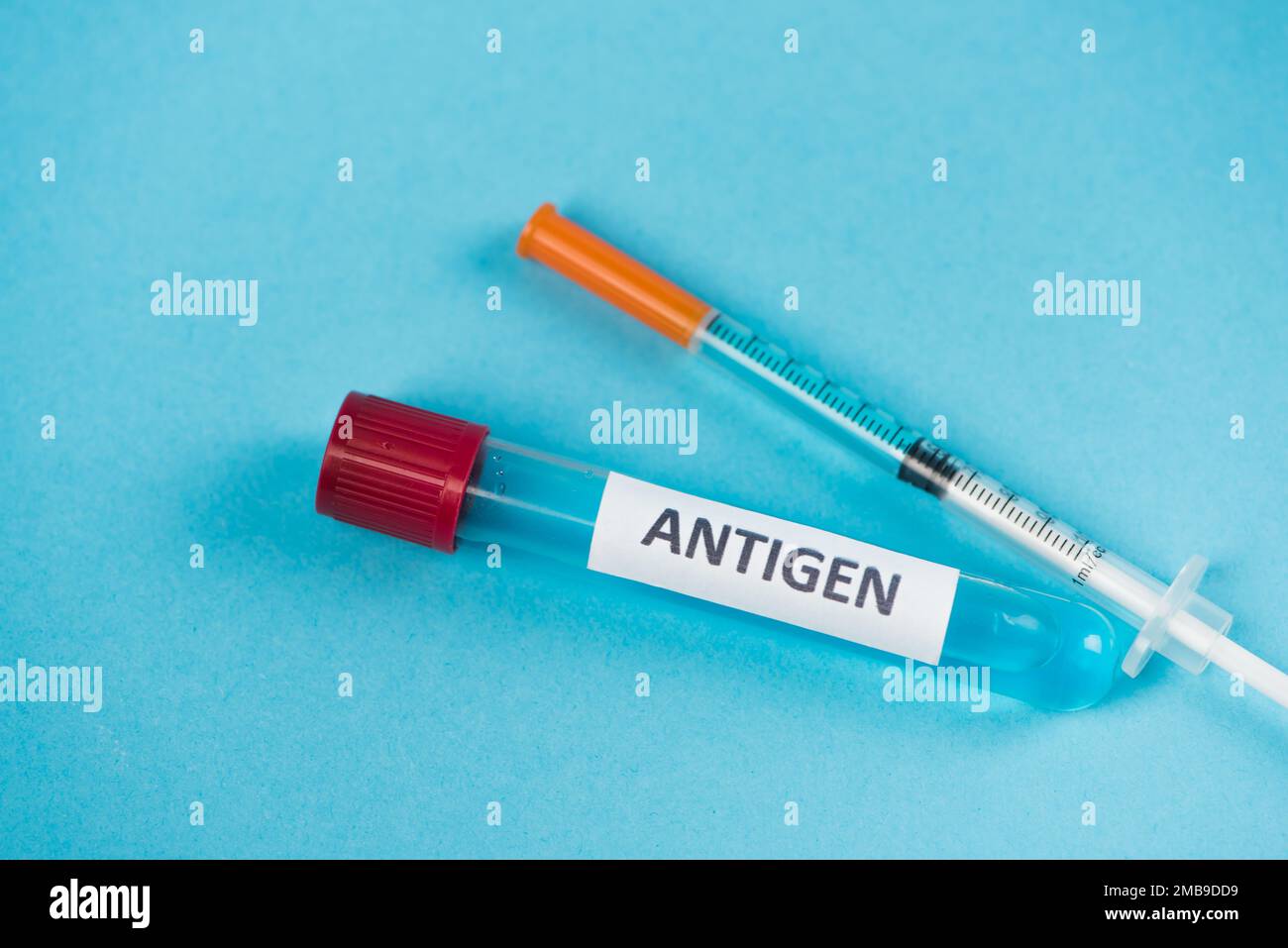 Close up view of syringe and test tube with antigen lettering on blue ...