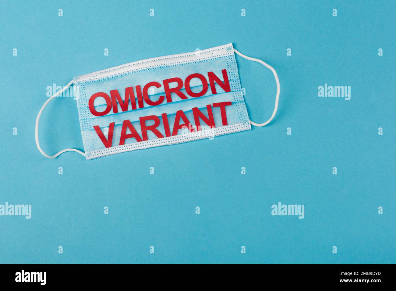 Top view of medical mask with omicron variant lettering on blue ...